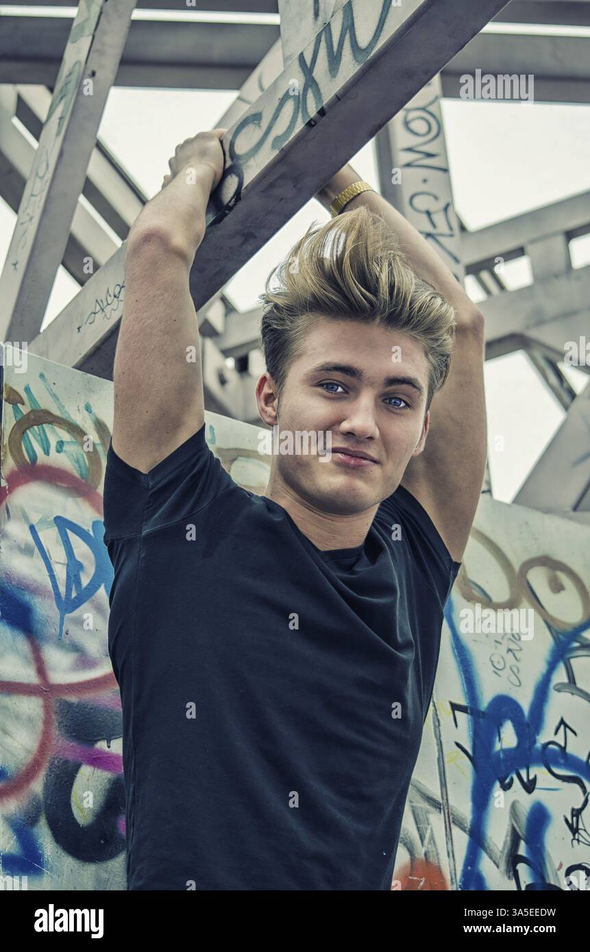 Attractive blue eyed, blond young man in black t-shirt hanging from ...