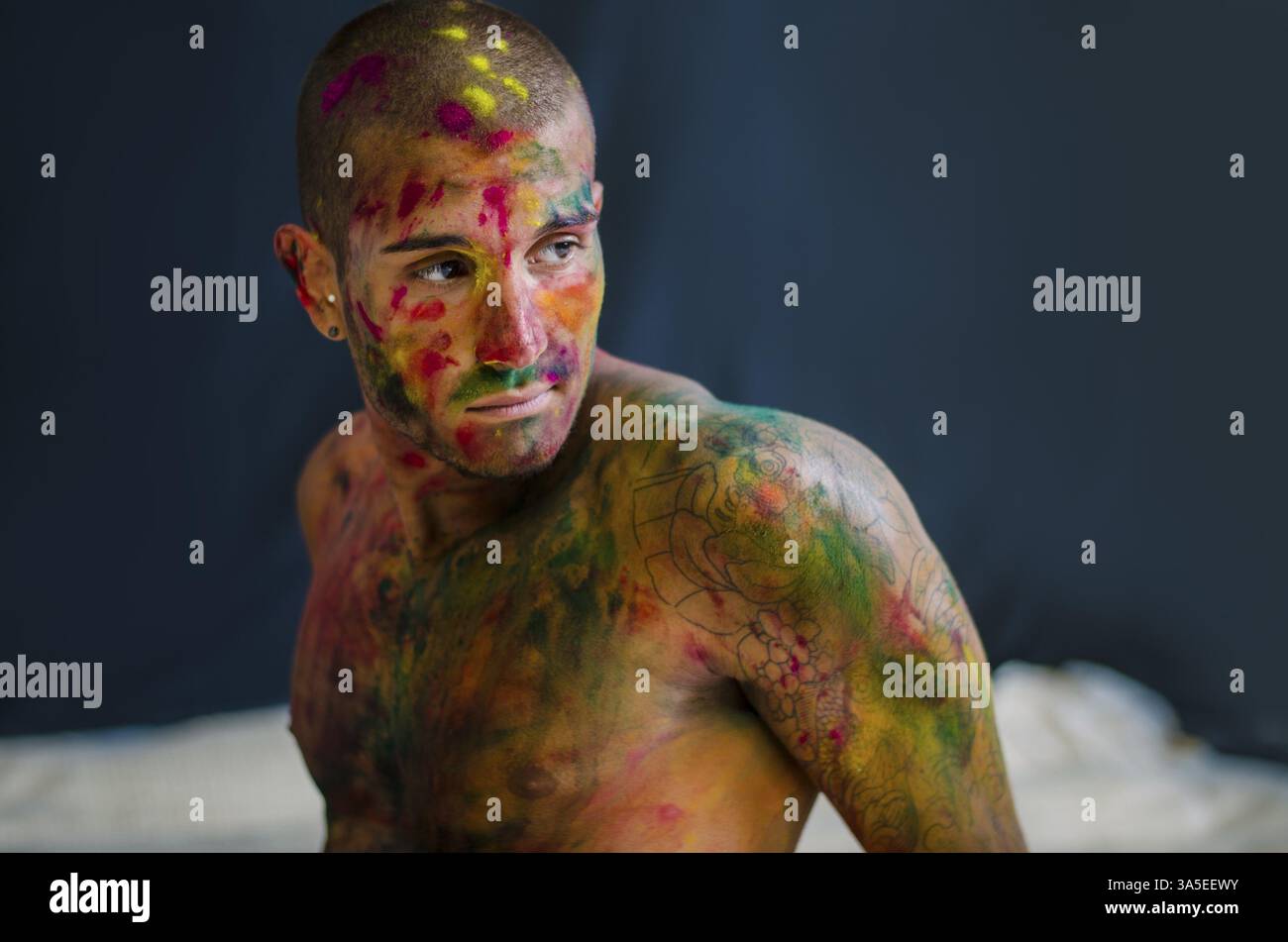 Side view of man, face painted with holi color powders.On dark ...