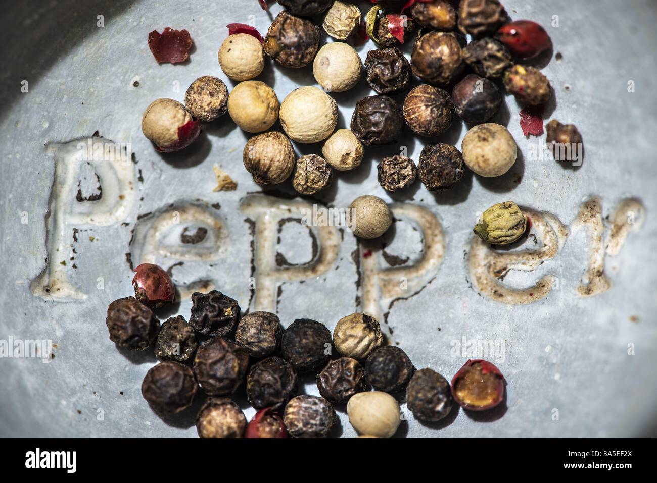 Black pepper in small bowl for spices on dark background. Red, green ...