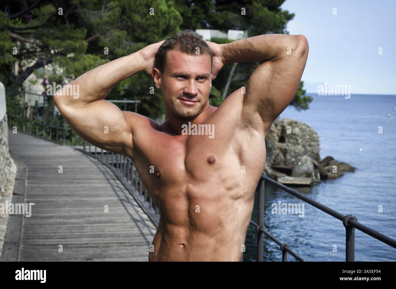 Attractive young muscle man smiling, outdoors, showing muscular body ...