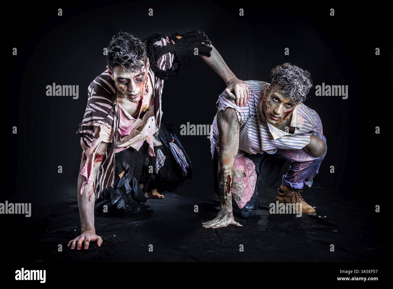 Two male zombies crawling on their knees, on black smoky background ...