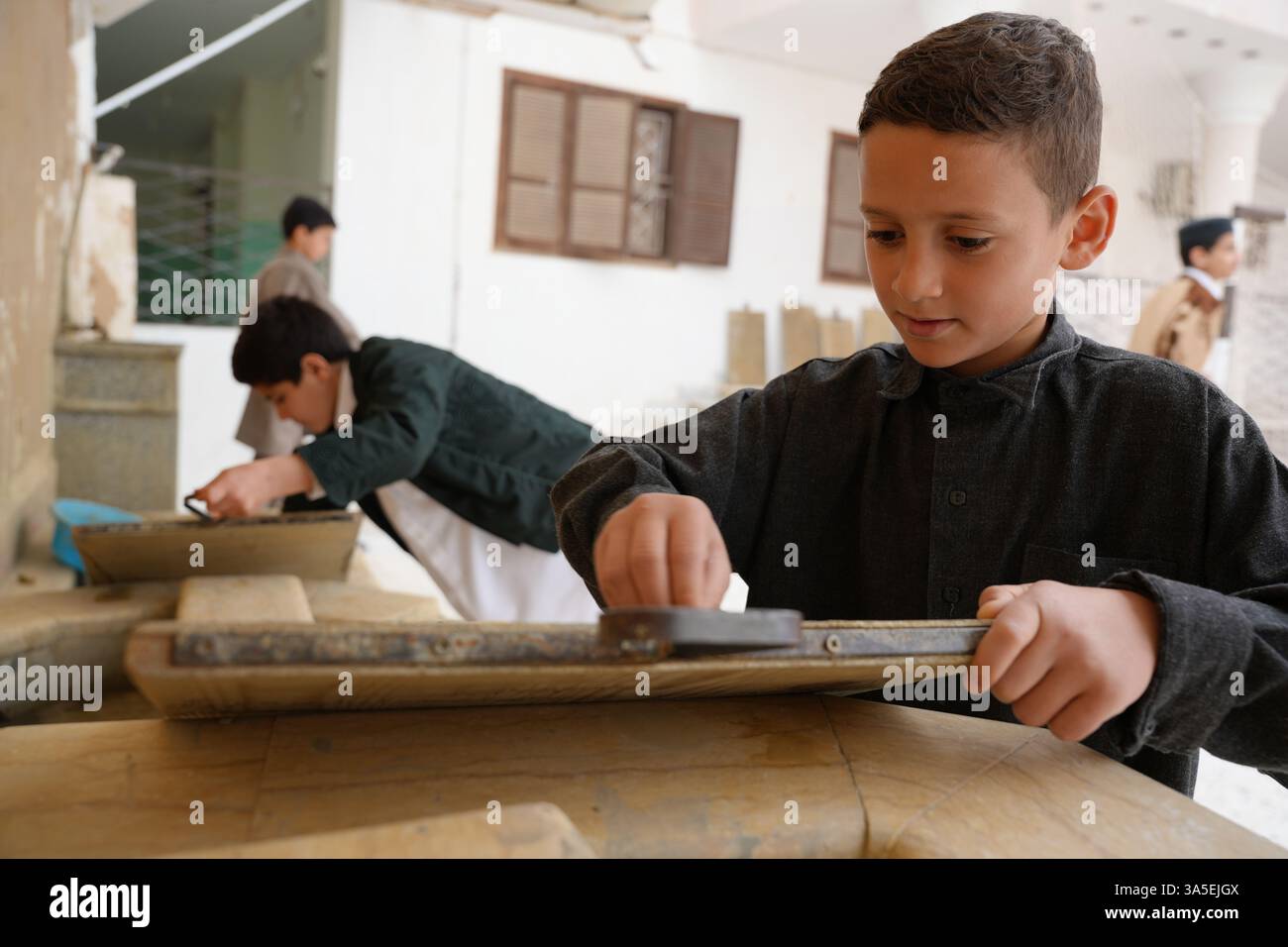 Students clean their wooden tablets with clay, wiping away the ...