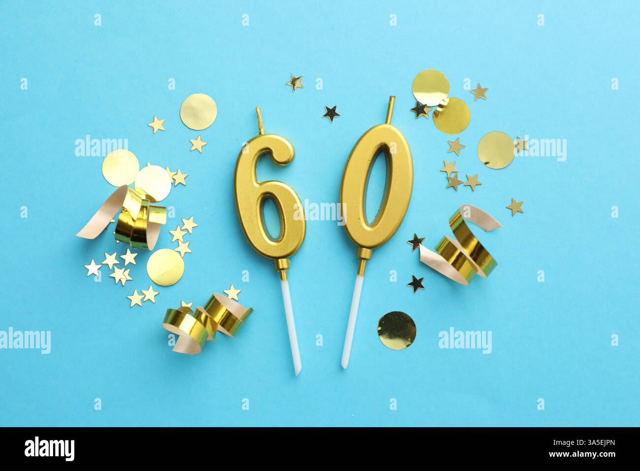 60th birthday. Number shaped candles and confetti on light blue ...