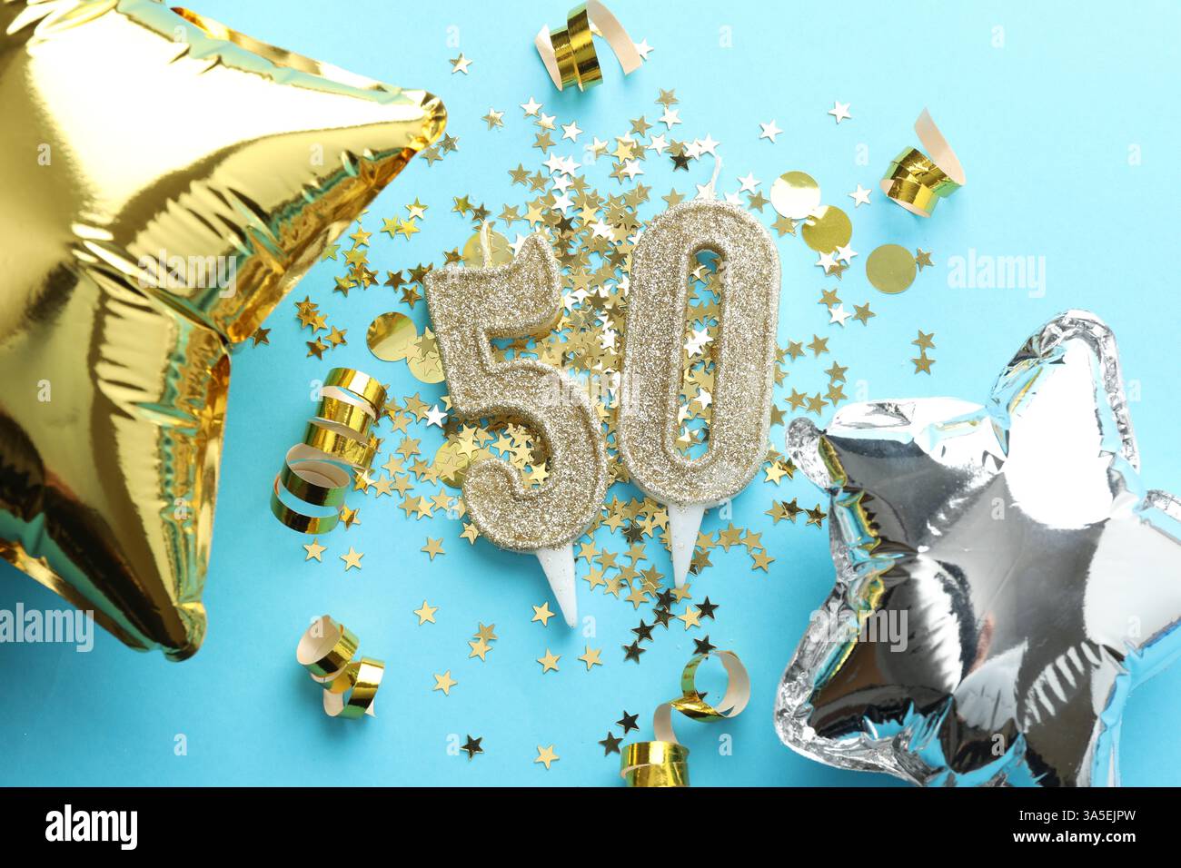 50th birthday. Number shaped candles, balloons and confetti on light ...