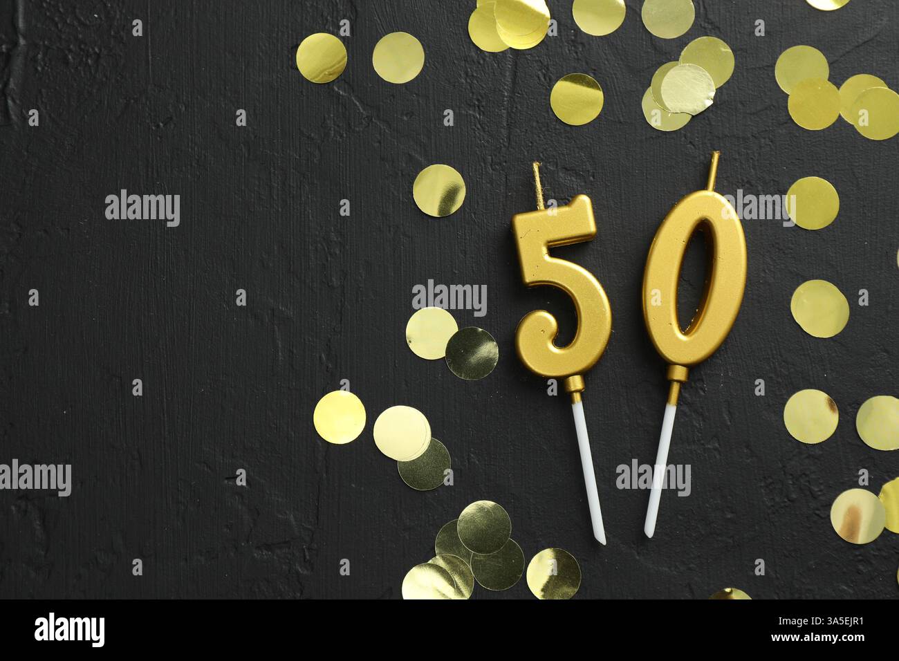 50th birthday. Number shaped candles and confetti on black background ...