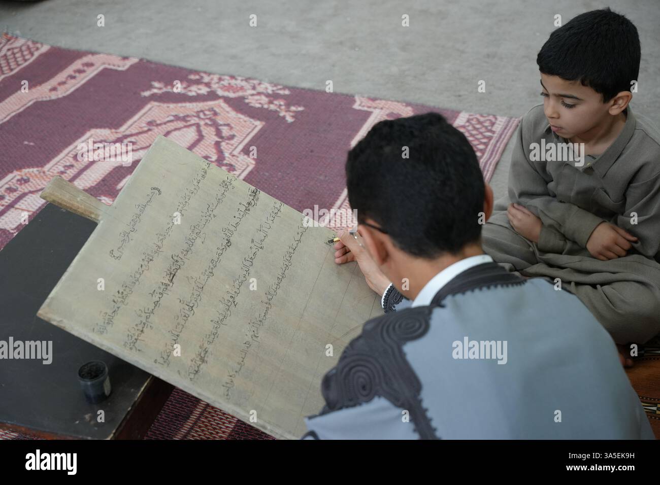 A student focuses on reading verses from the Holy Quran written on his ...