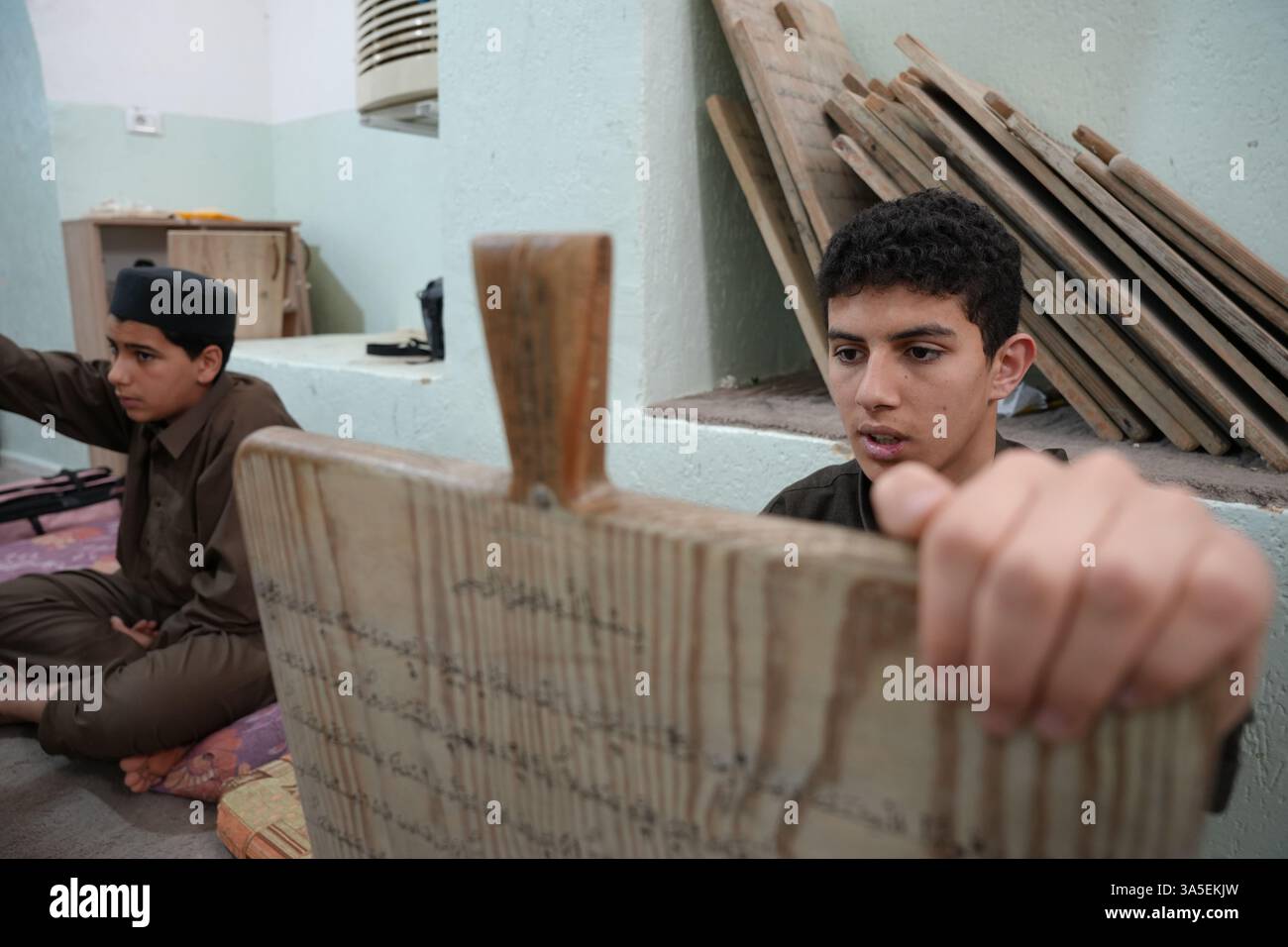 A student focuses on reading verses from the Holy Quran written on his ...