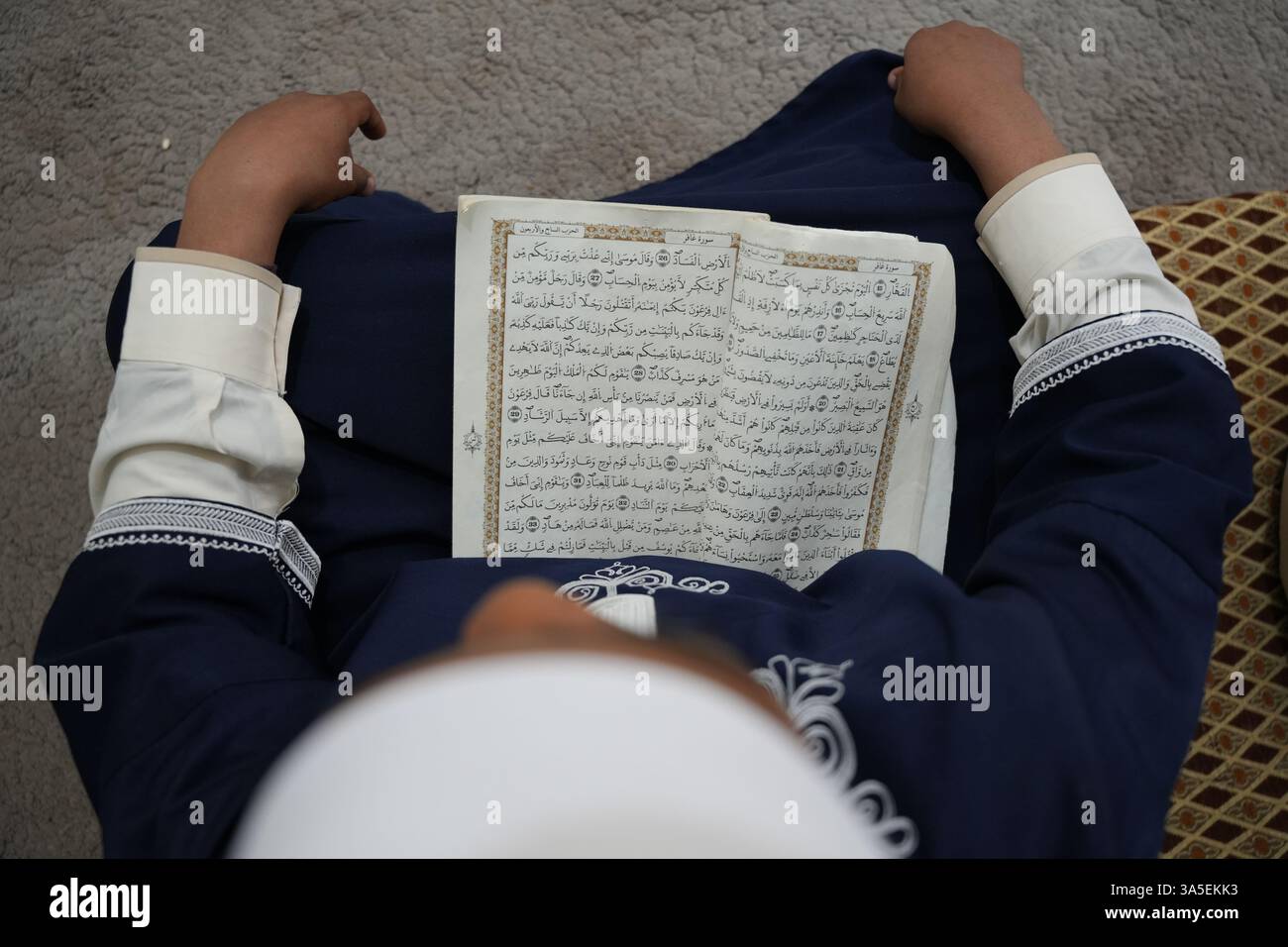 TOPSHOT – A student reads from the Holy Quran, seated in quiet focus ...