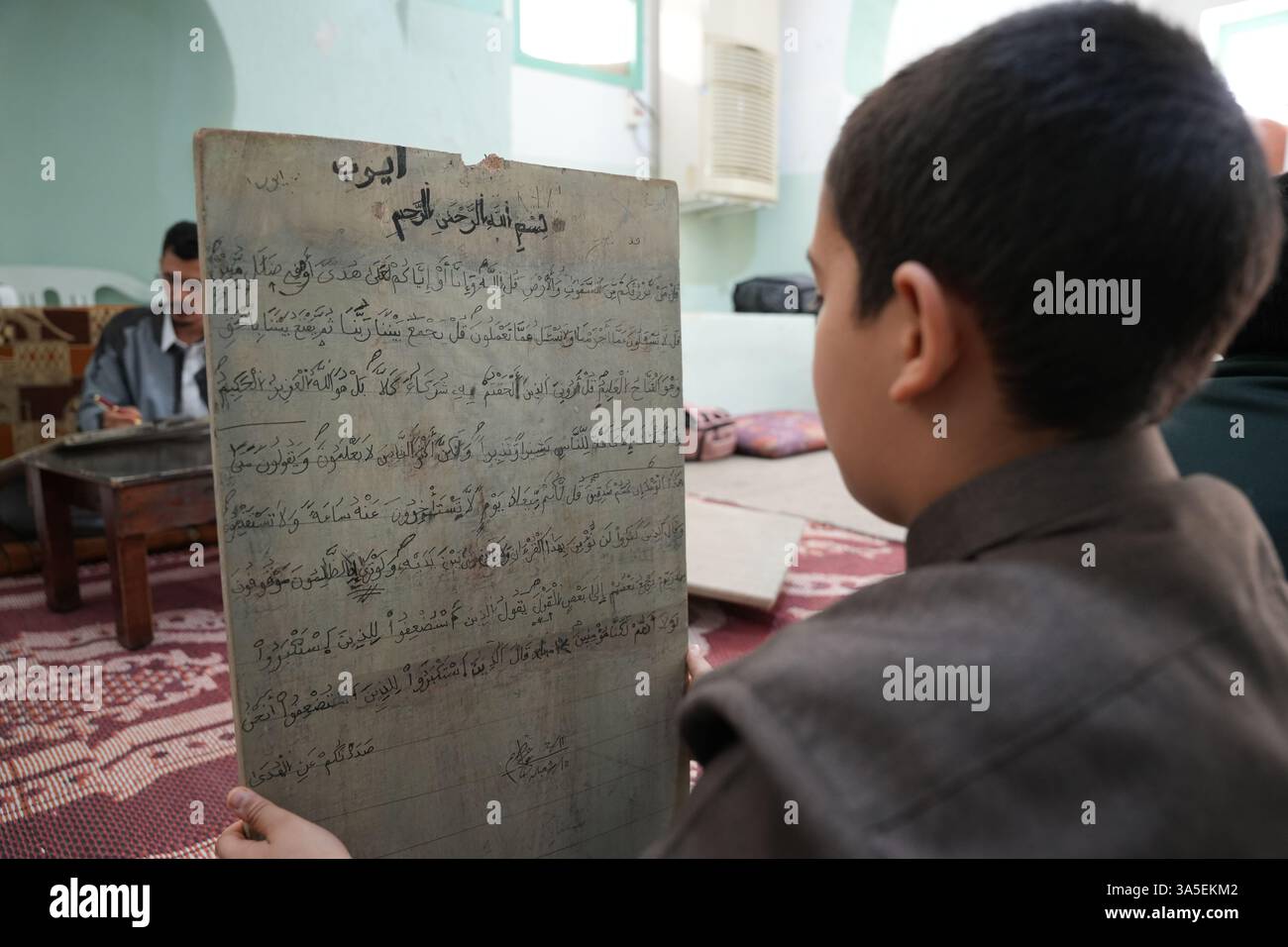 A student focuses on reading verses from the Holy Quran written on his ...