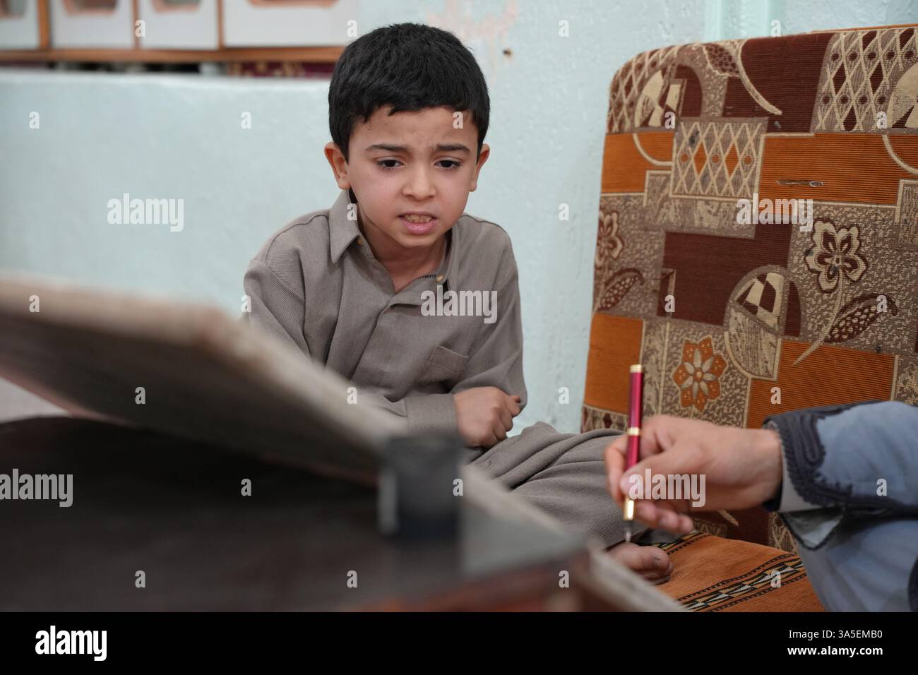 A student focuses on reading verses from the Holy Quran written on his ...