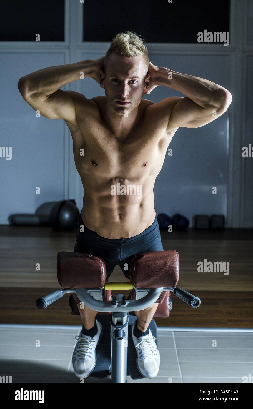 Attractive and fit young man in gym working out legs and exercising on ...