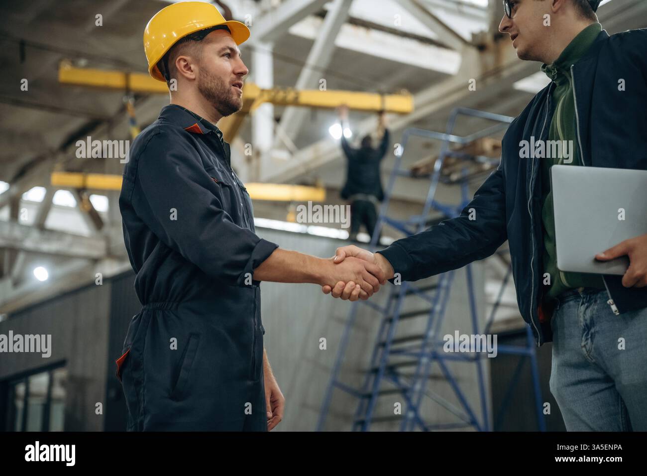 Friendly handshake. Two male factory workers are in the warehouse Stock ...