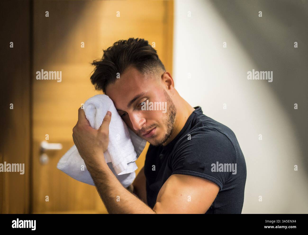 Muscular young bodybuilder drying sweat from his face with a towel ...