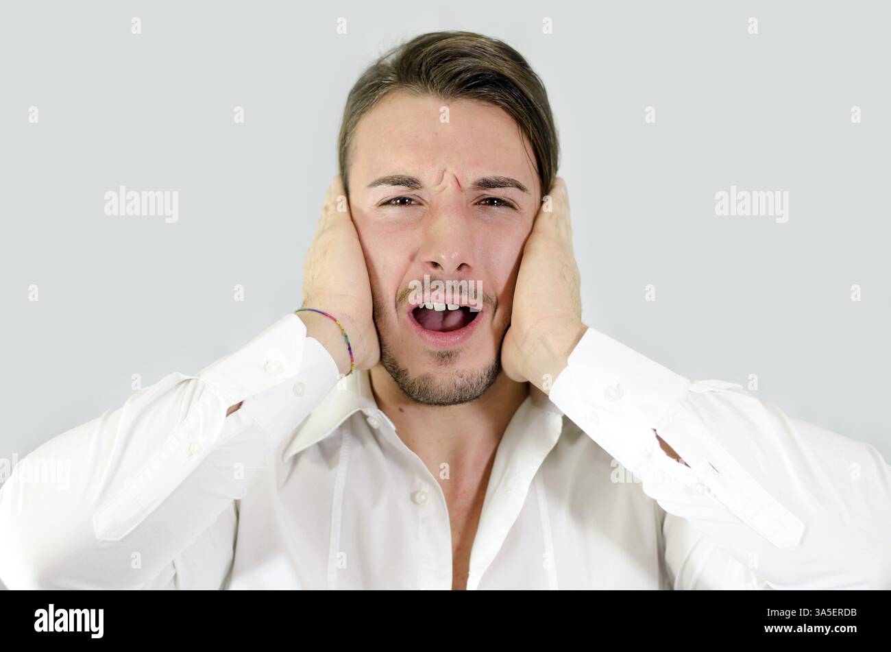 Irritated, frustrated, stressed guy covering his ears, too much noise Stock Photo - Alamy