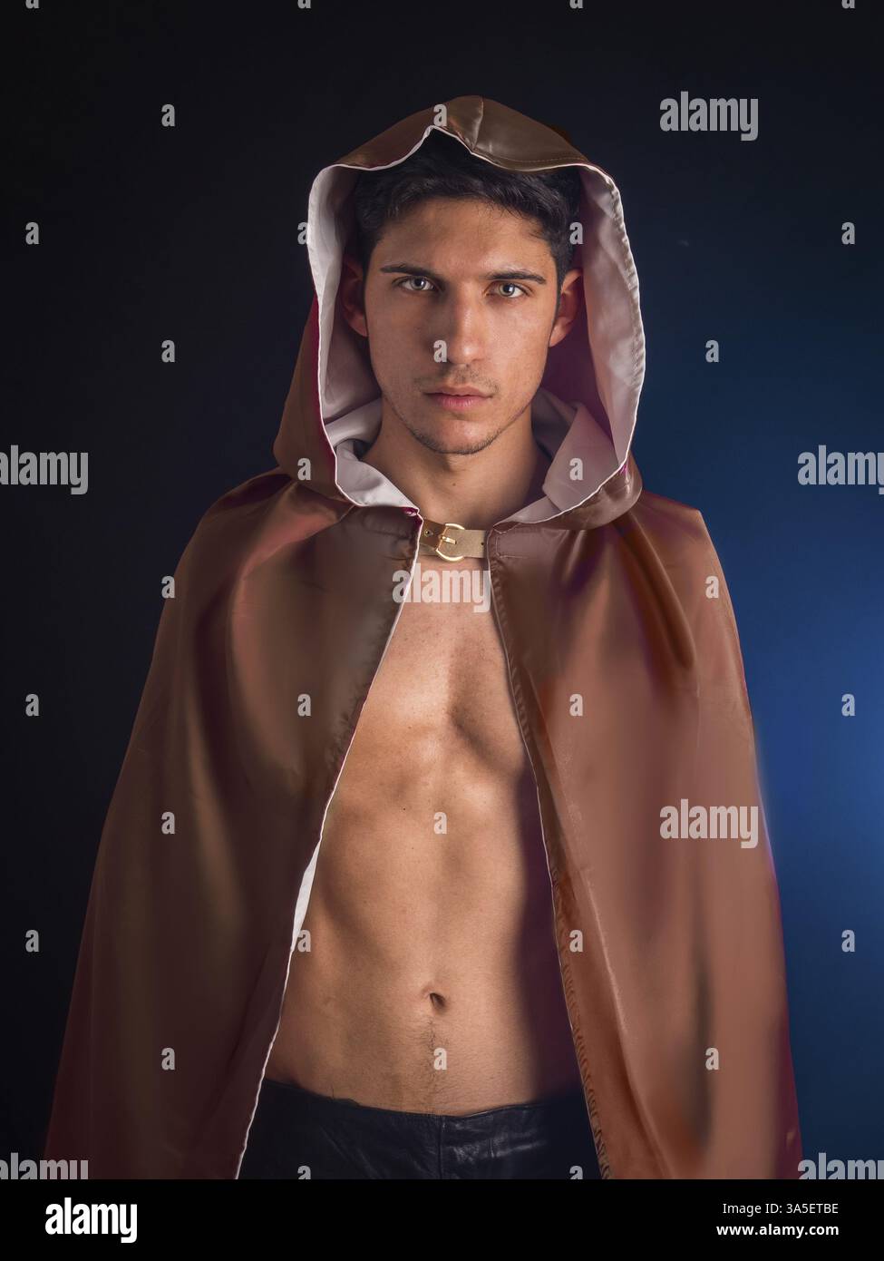 Handsome young man in old fashioned cloak on dark smoky background ...