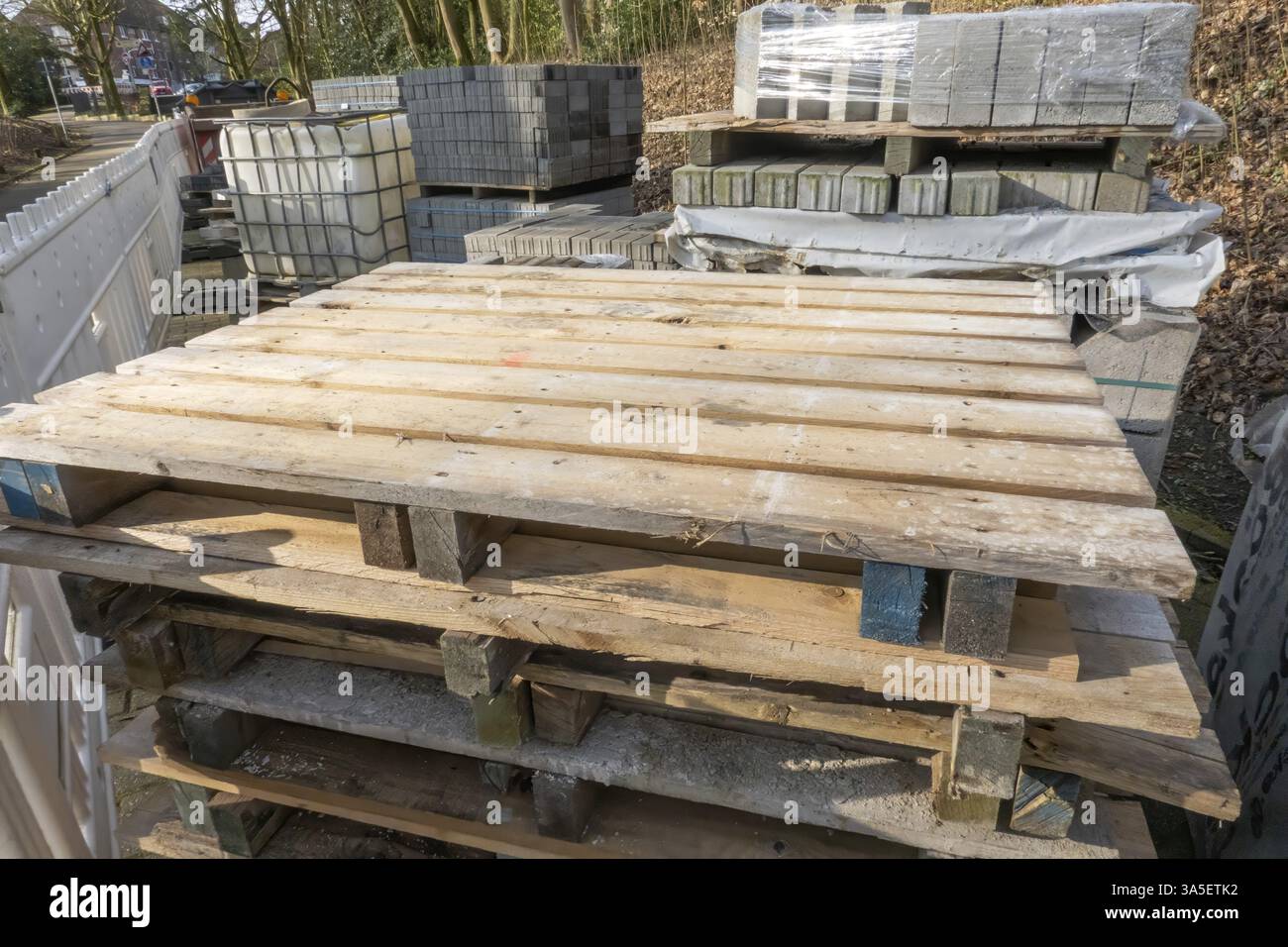 Wooden pallets stacked high, supporting various construction materials like concrete blocks and ...