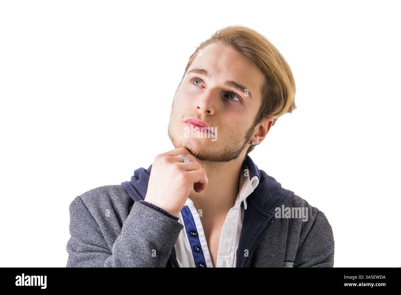 Attractive young man thinking, looking up with hand on his chin ...