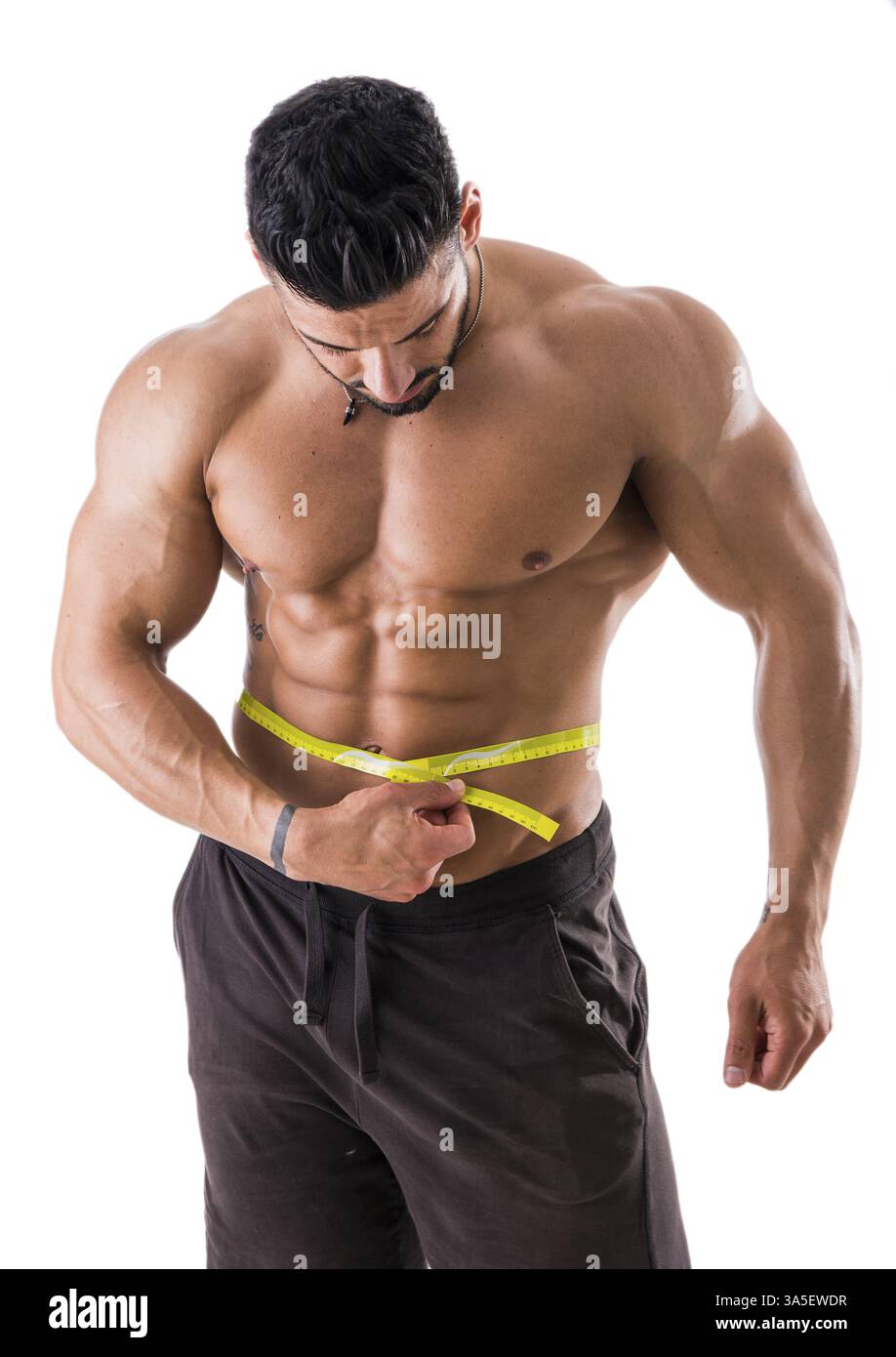Muscular bodybuilder man measuring belly and hips with tape measure ...