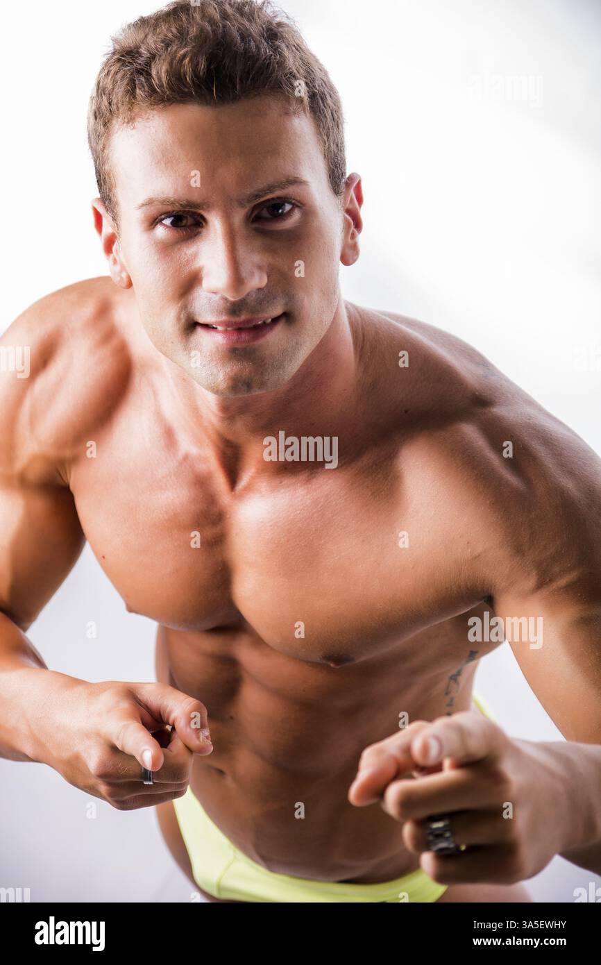 Muscular young bodybuilder in relaxed pose, smiling and looking at ...