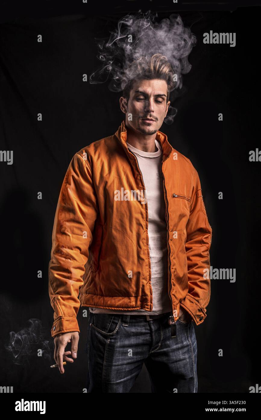 Handsome young man smoking cigarette, dressed as James Dean with red ...