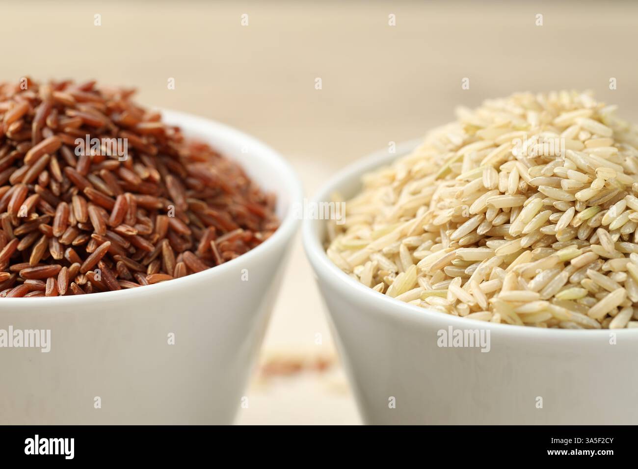 Different types of brown rice in bowls on blurred background, closeup ...