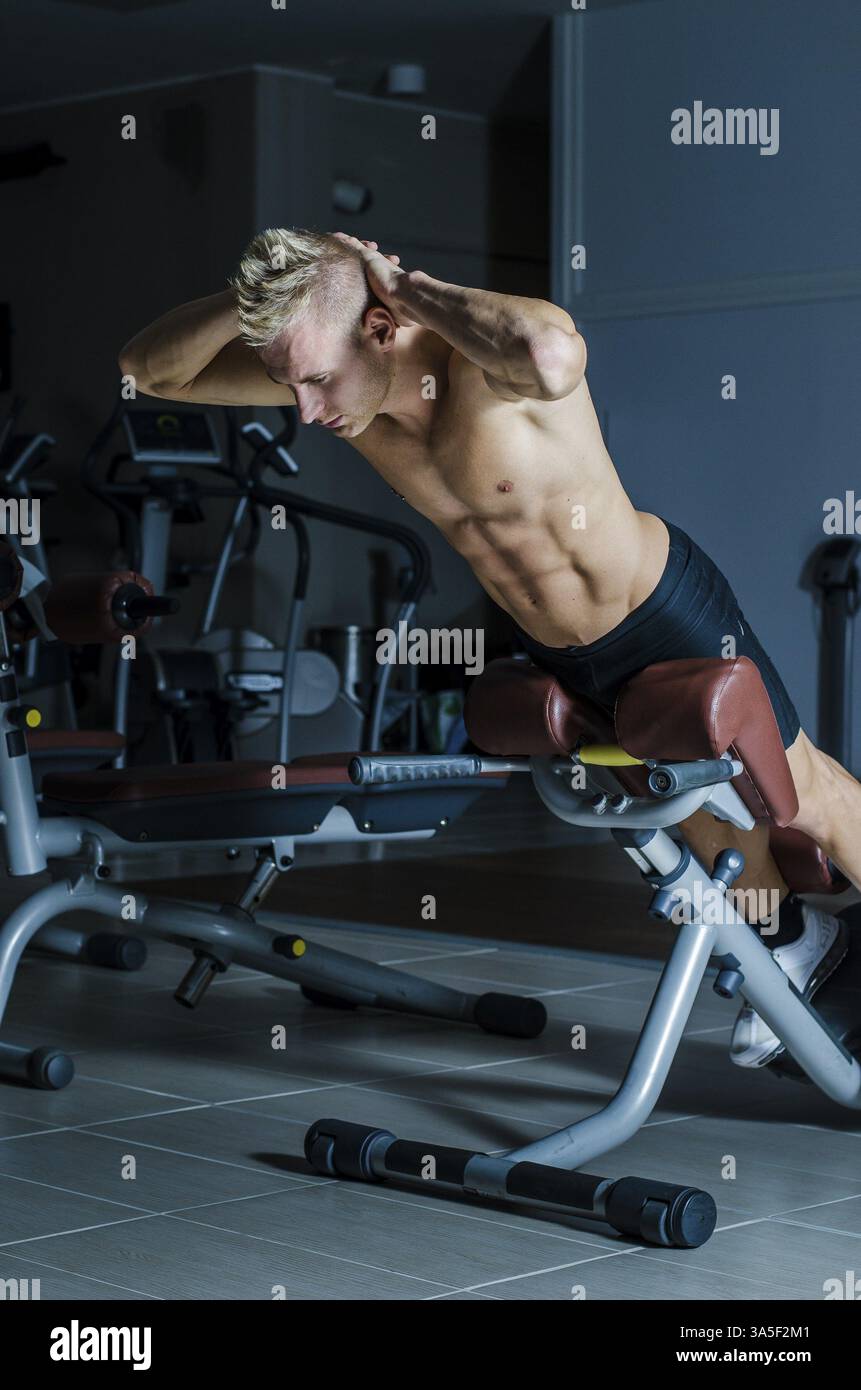 Attractive and fit young man in gym working out legs and exercising on ...