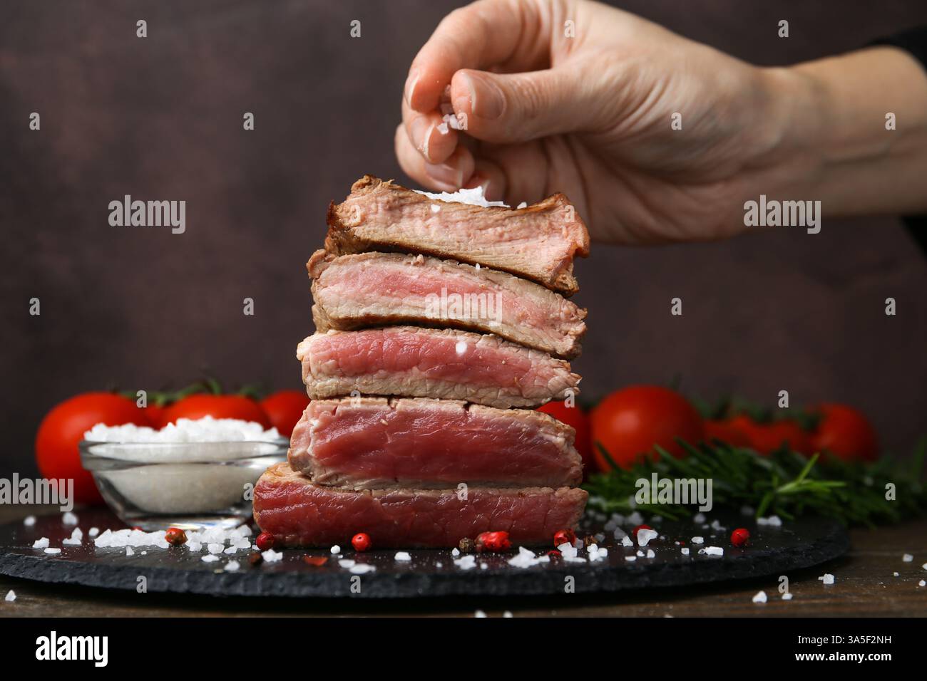 Woman salting delicious sliced beef tenderloin with different degrees ...