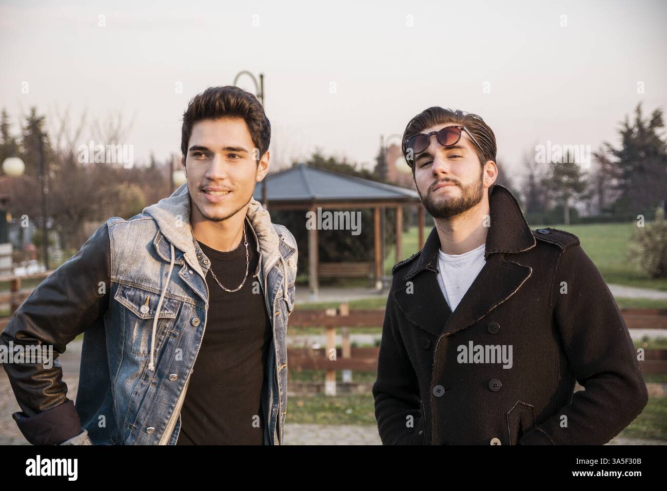 Two handsome casual trendy young men, 2 friends, in an urban park ...