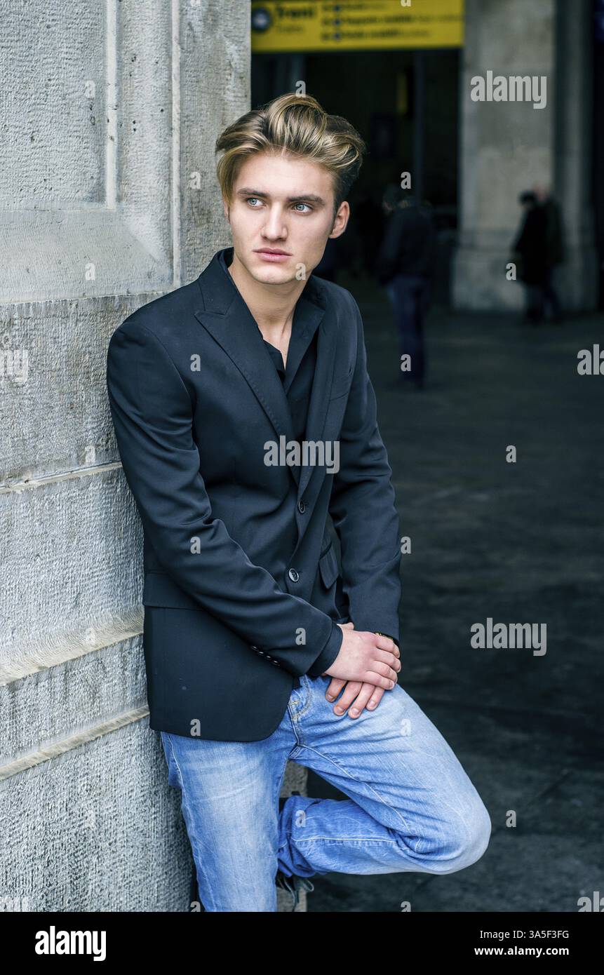 Attractive blue eyed, blond young man leaning with his back against ...