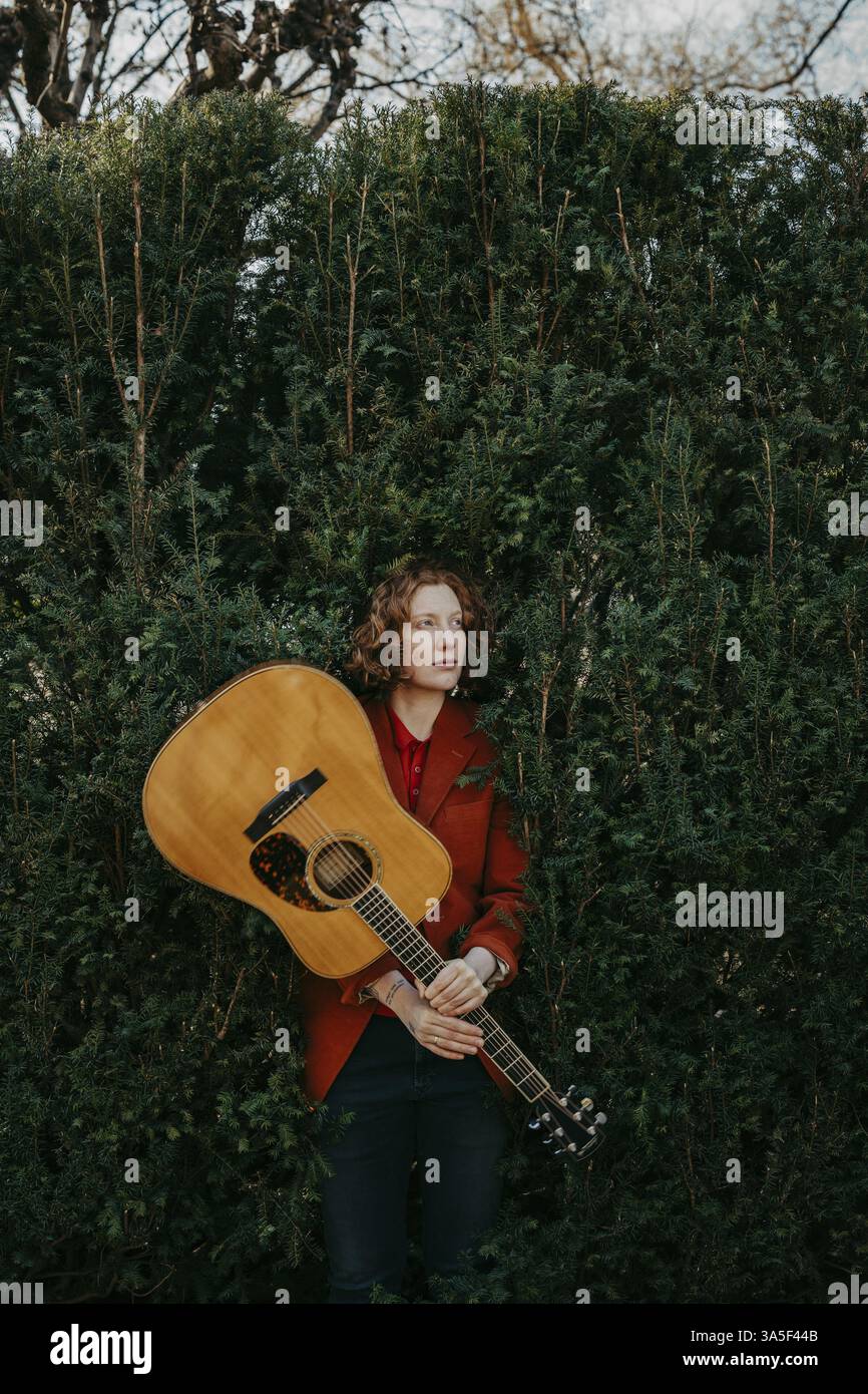 Red-haired guitarist with guitar in the green bush Stock Photo - Alamy