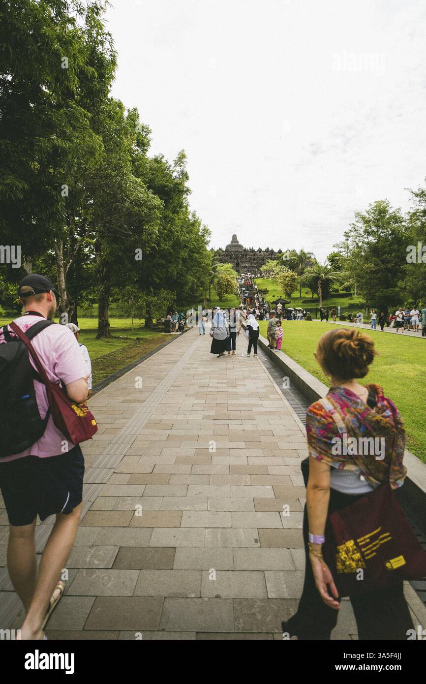 Visitors take a relaxed stroll along a tree-lined path to the temple ...