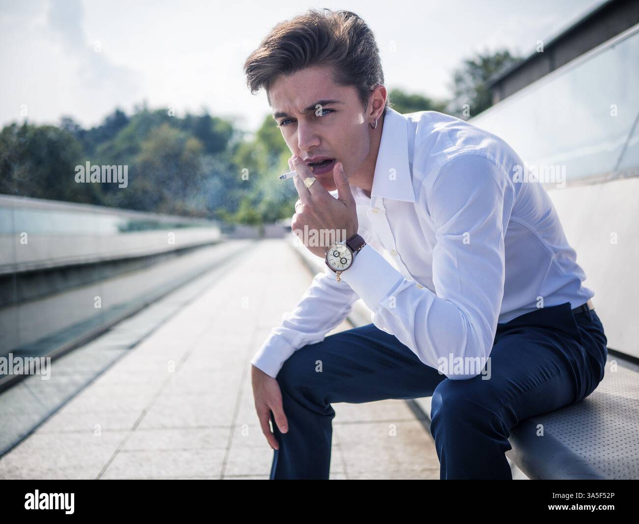 One handsome elegant young man smoking cigarette in urban setting in ...