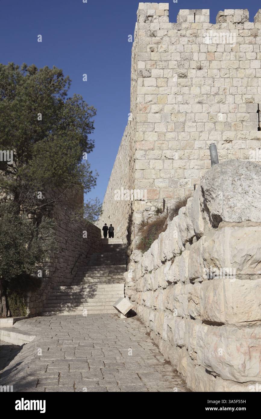 Two religious Jews in traditional clothes go along the Jerusalem wall ...