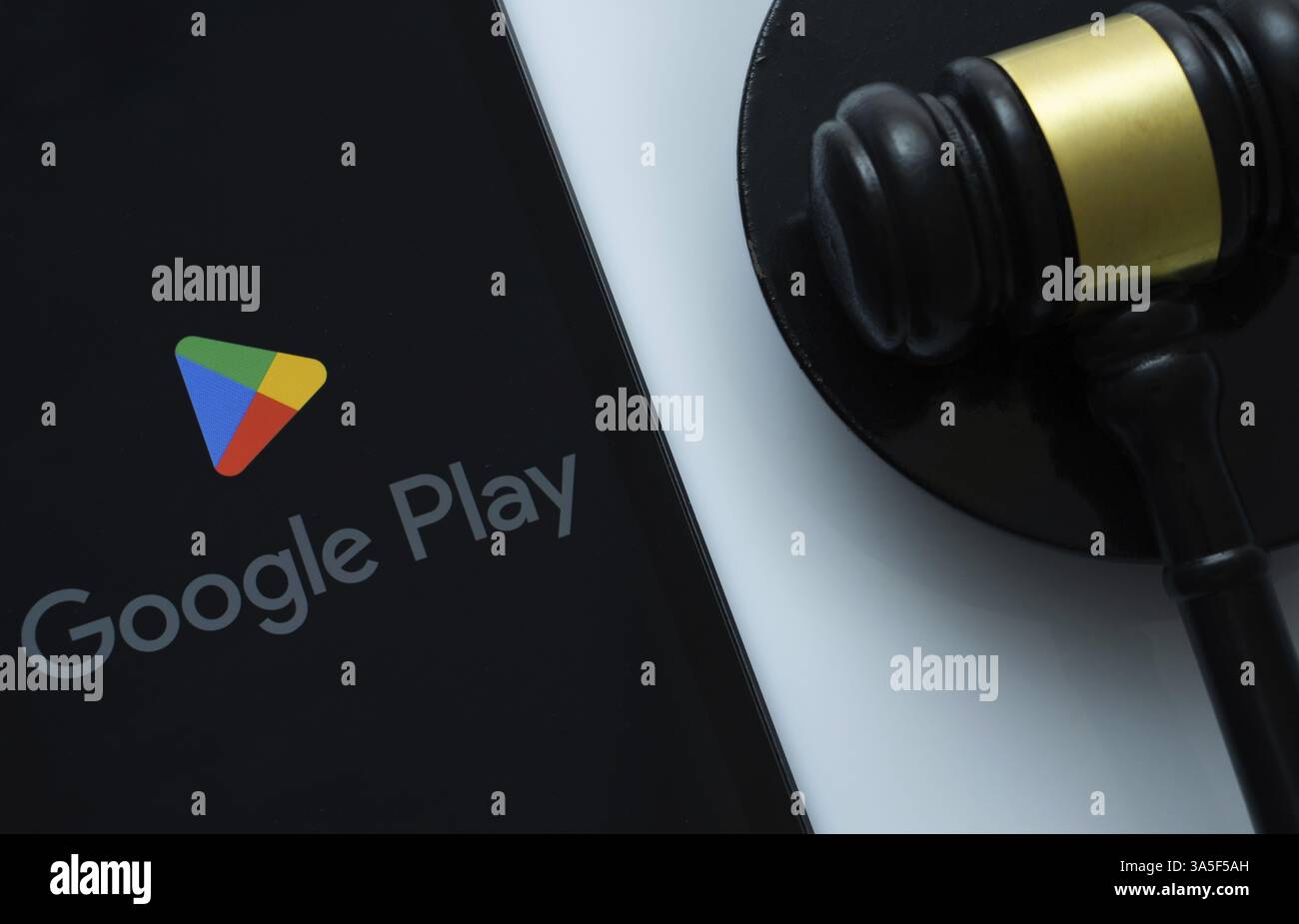 A close up of an iPad screen displaying the google play app alongside a judge's gavel Stock ...