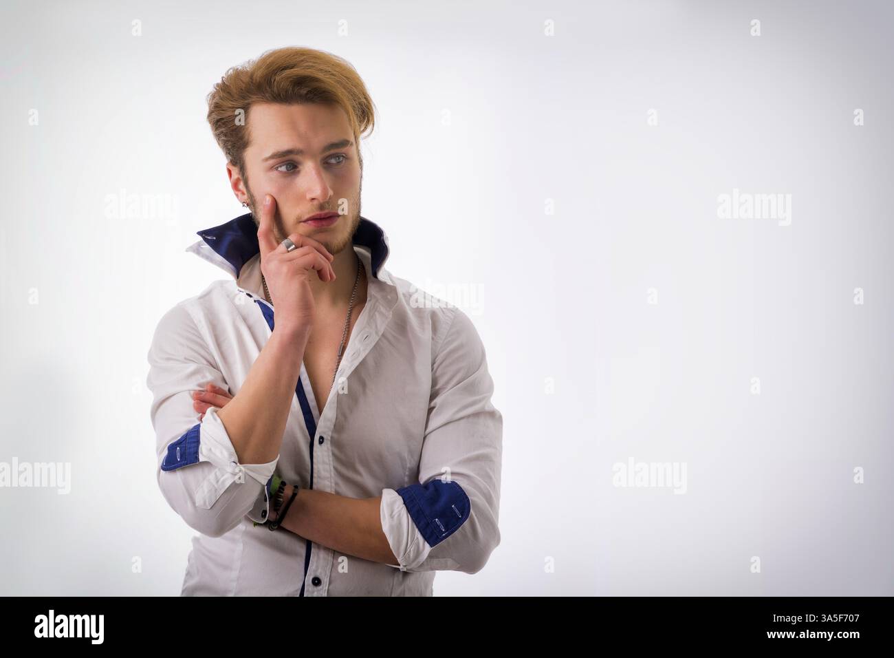 Attractive young man thinking, looking up with hand on his chin, on ...