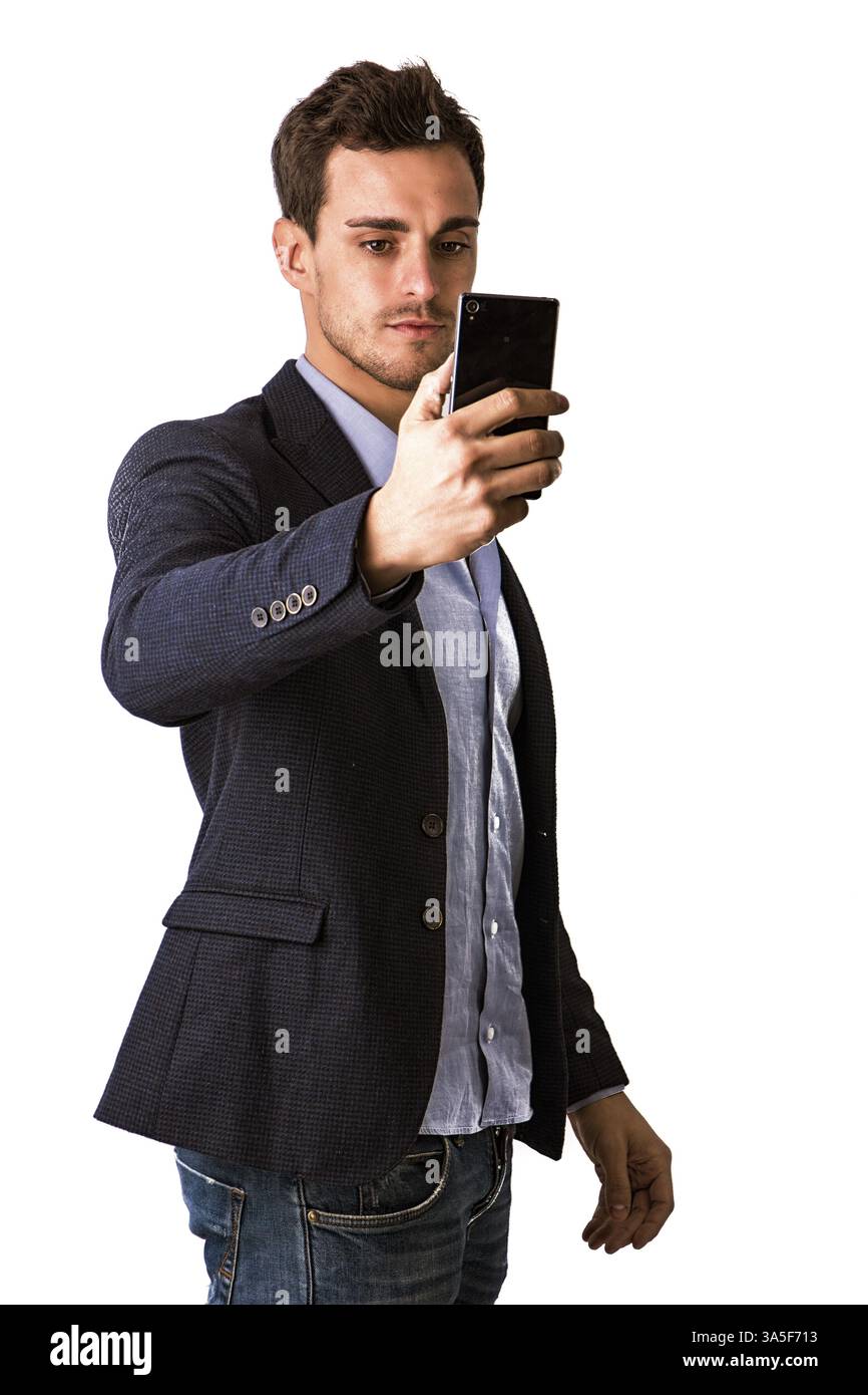 Handsome man taking selfie photo on cell phone or mobile, on black background in studio shot ...