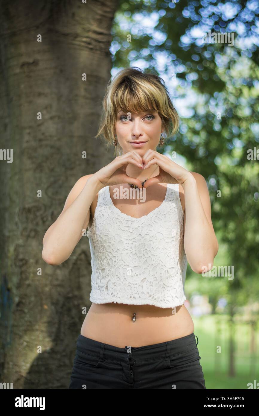 Pretty blonde young woman doing heart sign with hands as a symbol of ...