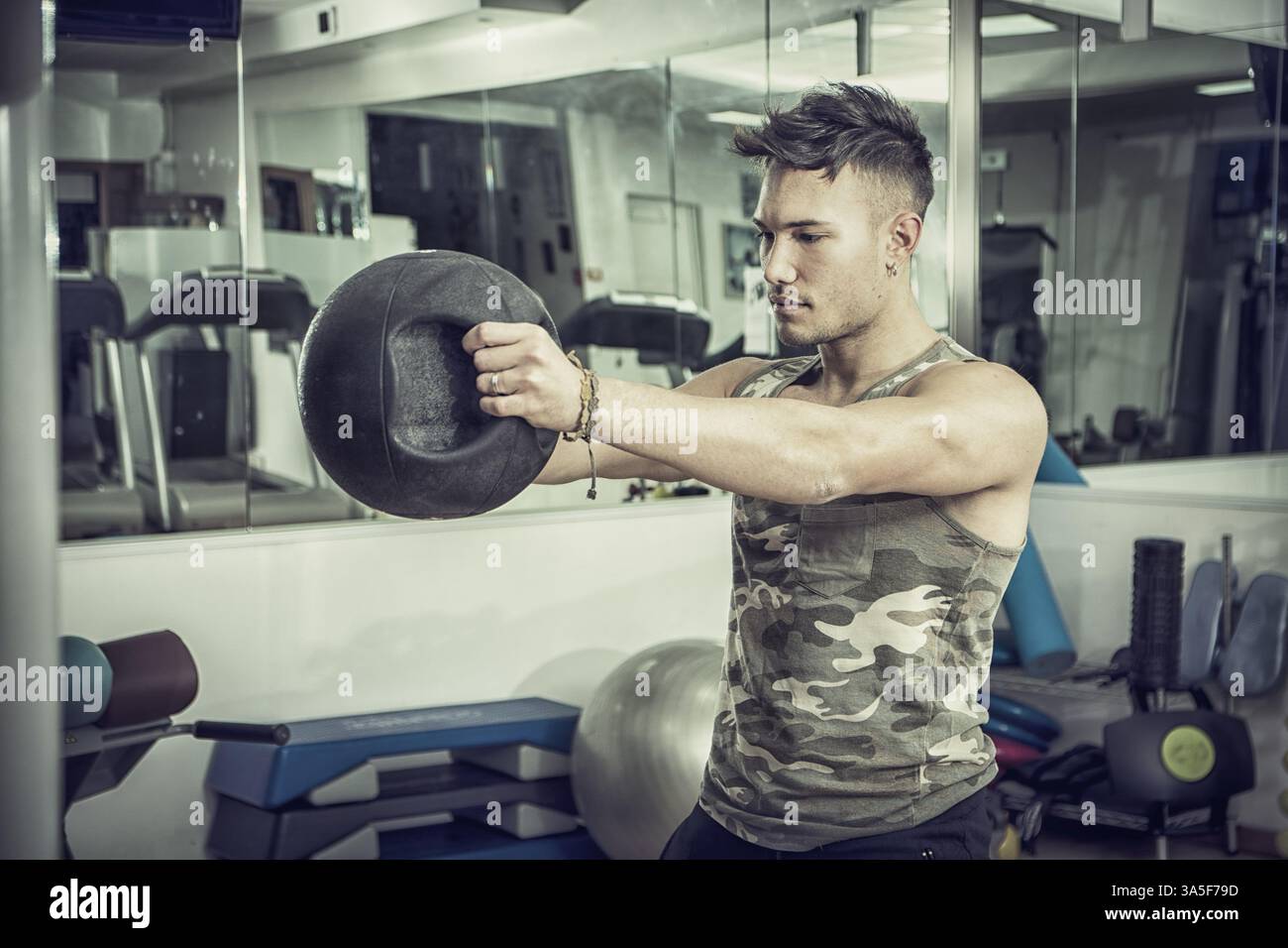 Attractive young athletic man exercising in gym, working out using ...