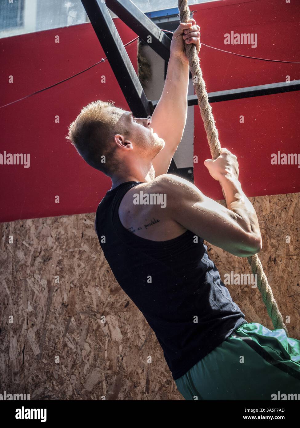 Handsome muscular young man athlete exercising in gym, hanging and ...