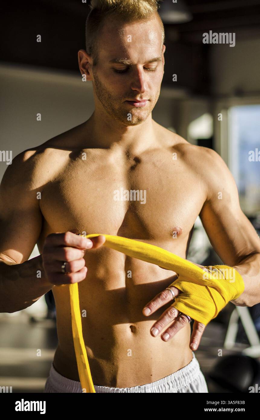 Muscular young man wrapping bandage around his hands for boxing Stock ...