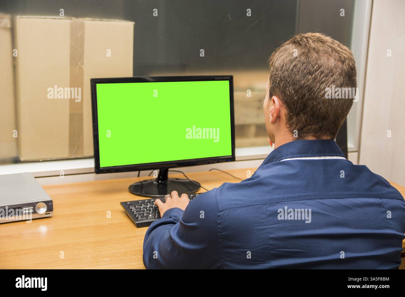 Young office male worker sitting at his desk working at computer, seen ...