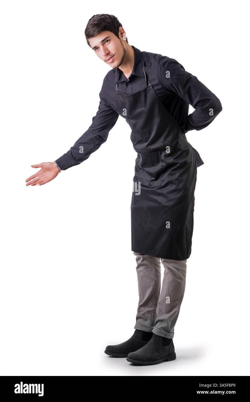 Young chef or waiter posing, wearing black apron and shirt isolated on ...