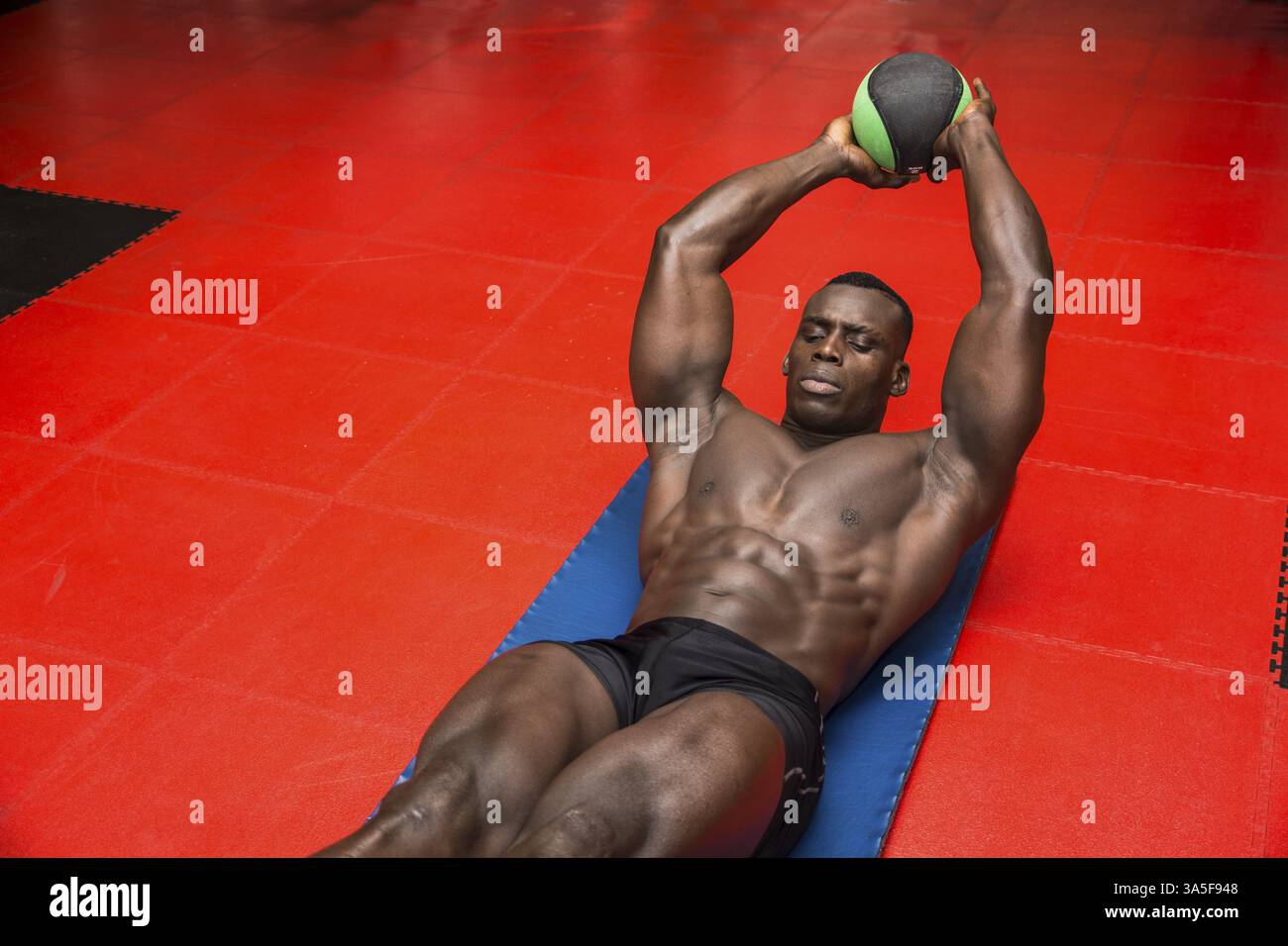 Hunky muscular black bodybuilder working out in gym, exercising abs ...
