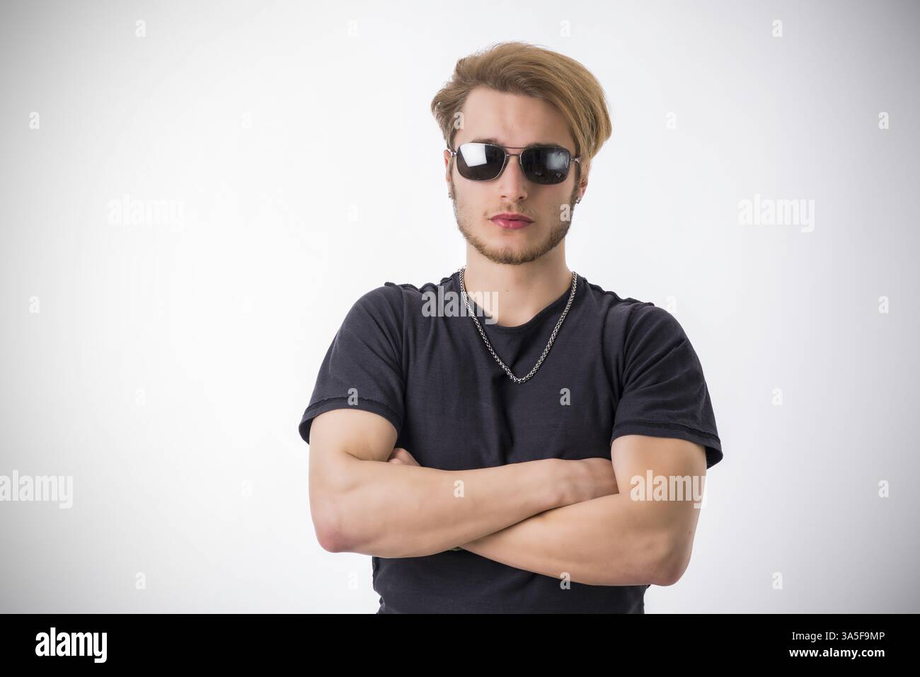 Portrait of handsome blond young man, with arms crossed on chest ...