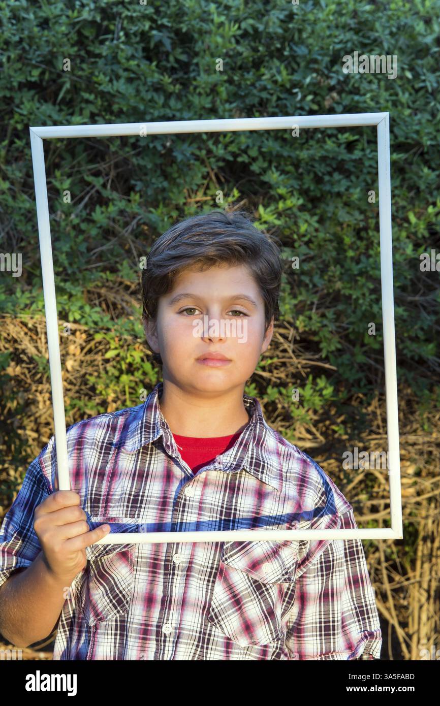 Smart intelligent handsome boy is looking through a white frame ...