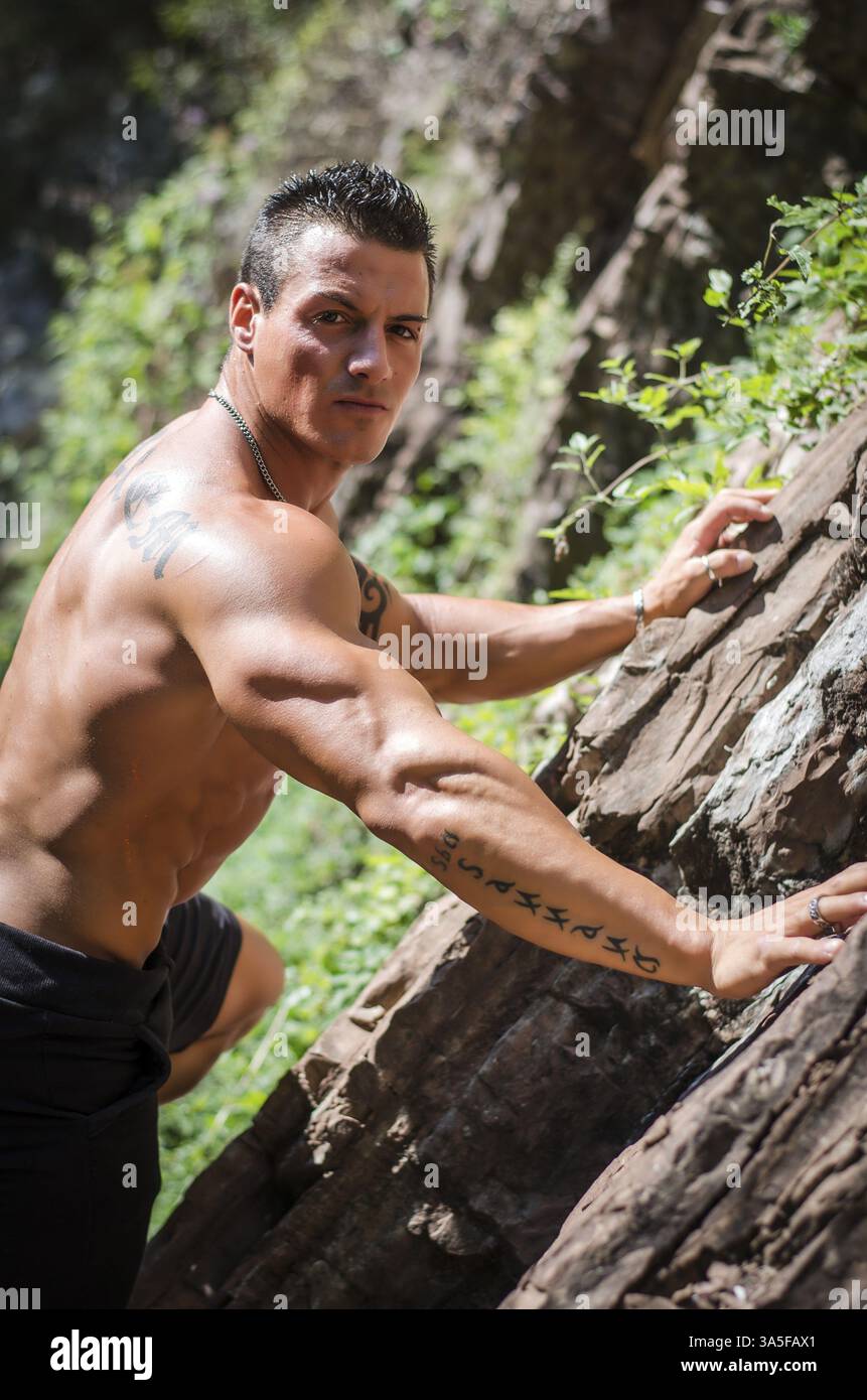 Handsome, muscular, shirless climber, looking in camera and climbing ...