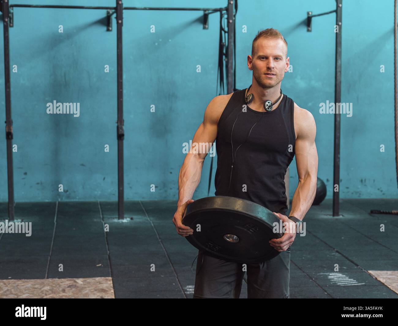 Handsome muscular young man holding big weight plate Stock Photo - Alamy