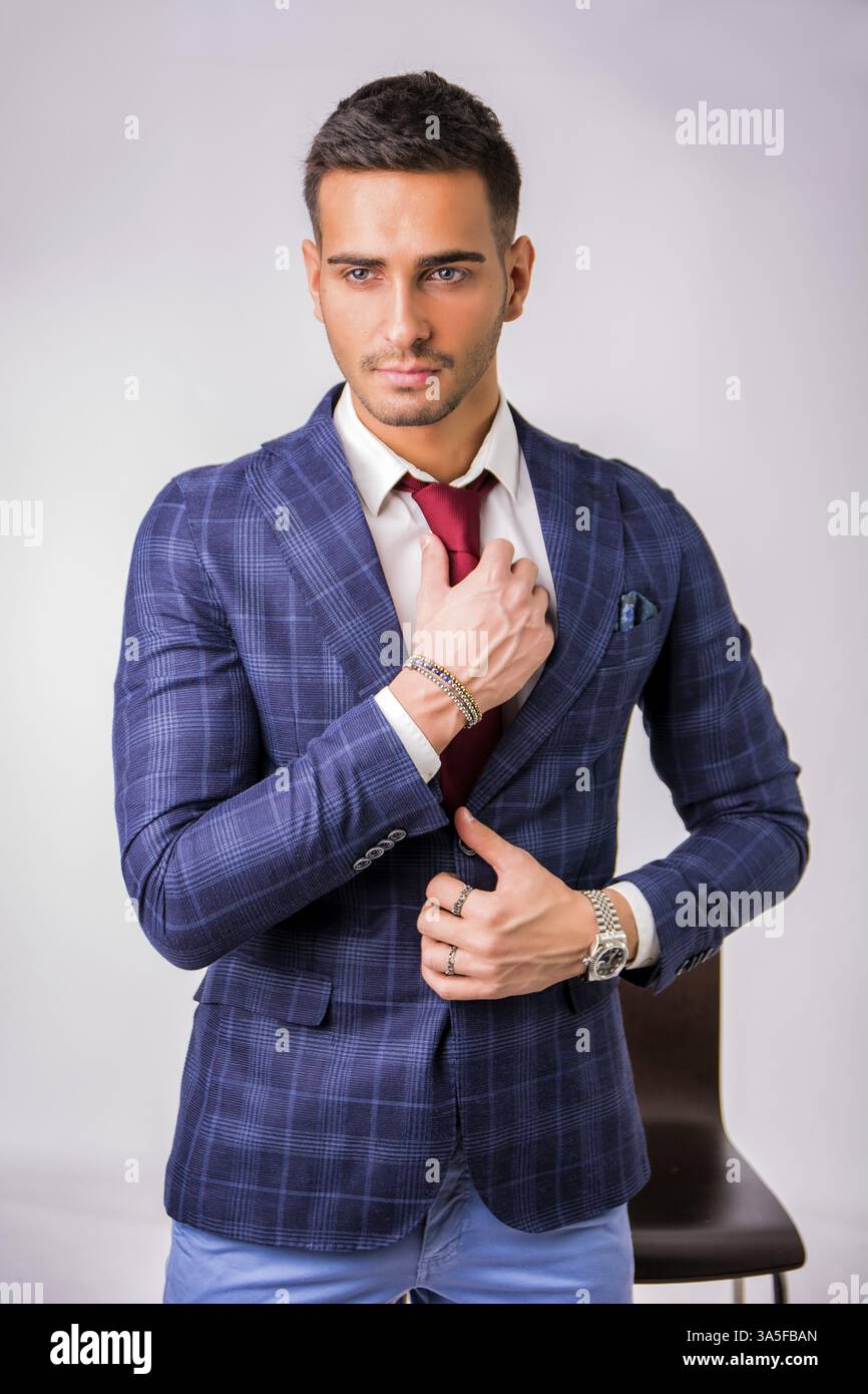 Handsome young man in blue business jacket and jeans posing on light ...