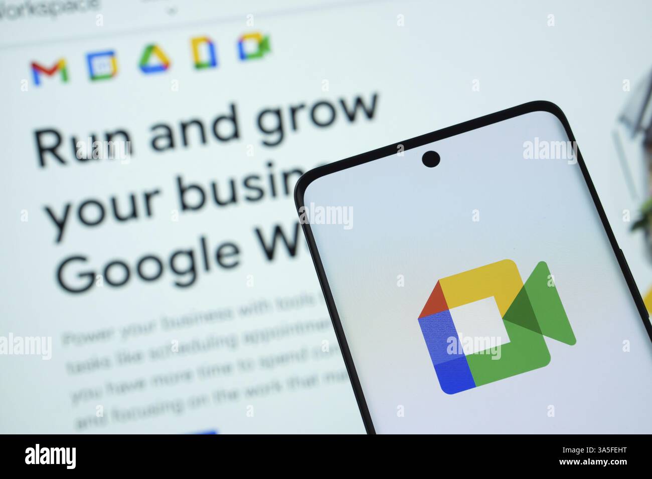 The logo of the Google Meet is displayed on a smartphone screen, and ...