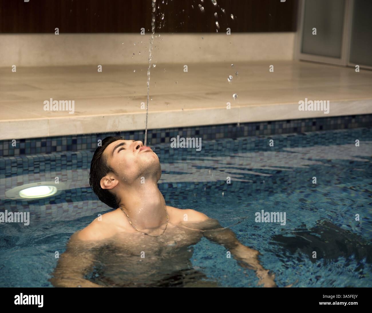 Young Man in Swimming Pool Playing, Spitting and Spraying Water Up with ...